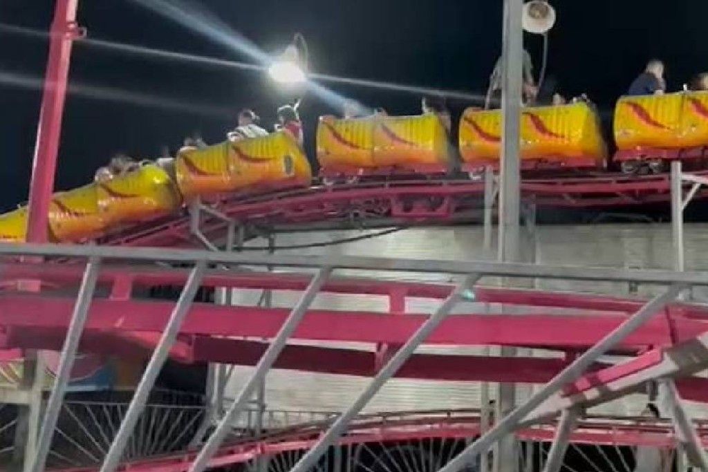 Brinquedo quebra com pessoas no alto dos trilhos em parque de diversões